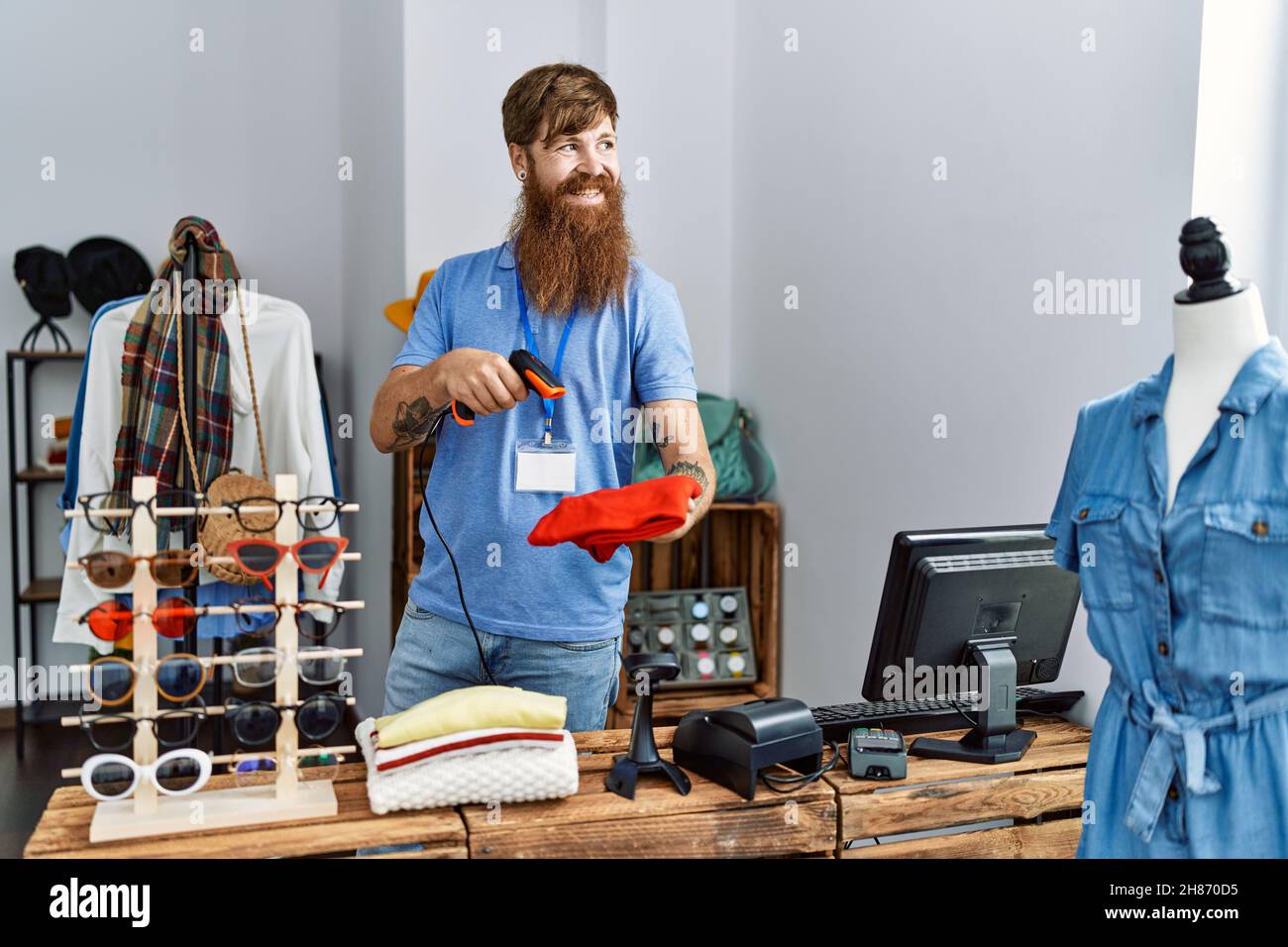 Young irish shopkeeper man smiling happy working at clothing store ...