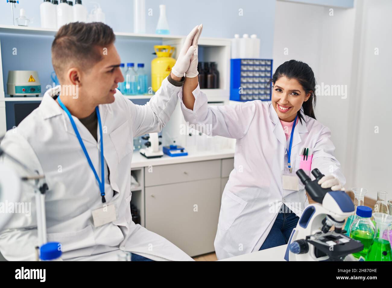 Man and woman scientists partners high five with hands raised up at ...