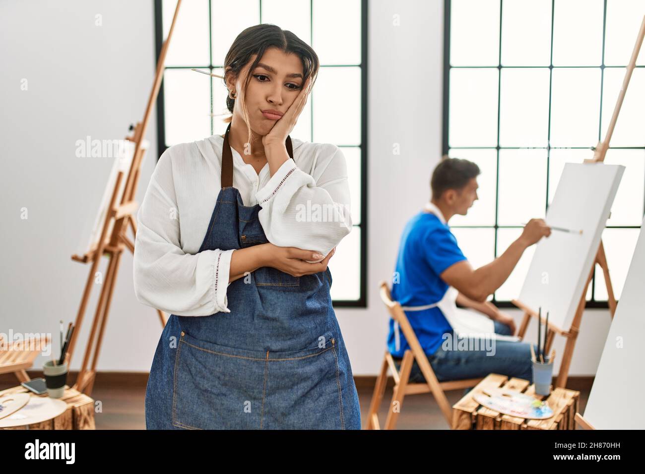 Young hispanic couple at art studio thinking looking tired and bored ...