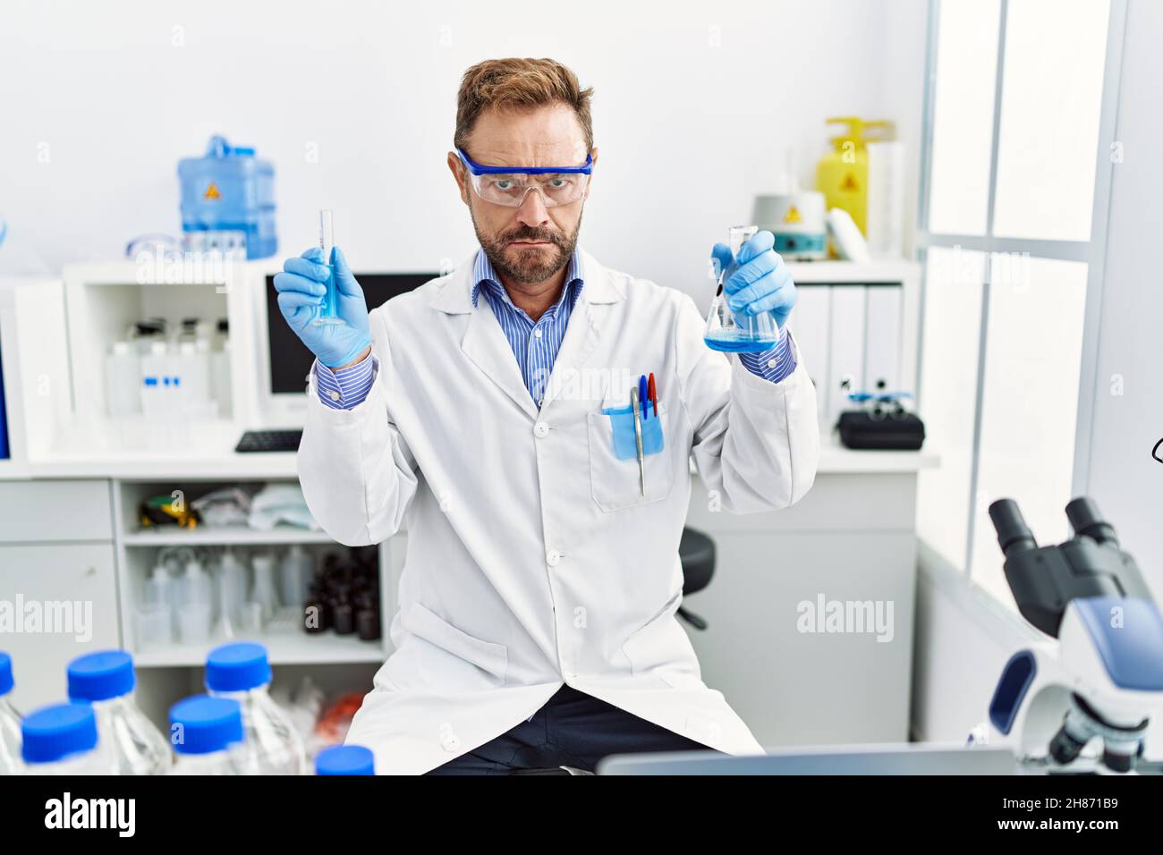 Middle age man working at scientist laboratory holding chemical ...