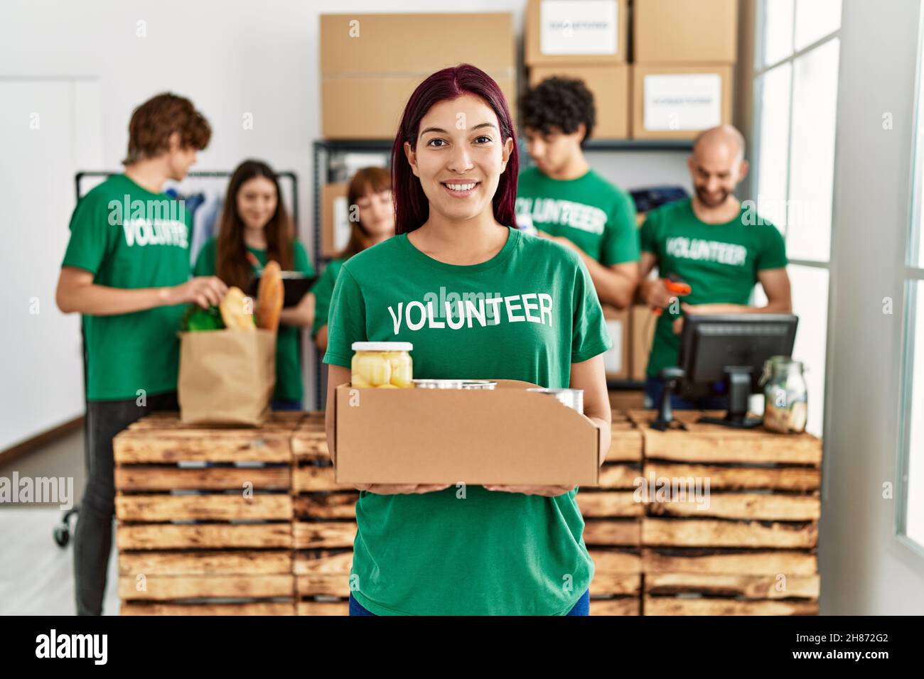 Group of young volunteers working at charity center. Woman smiling ...
