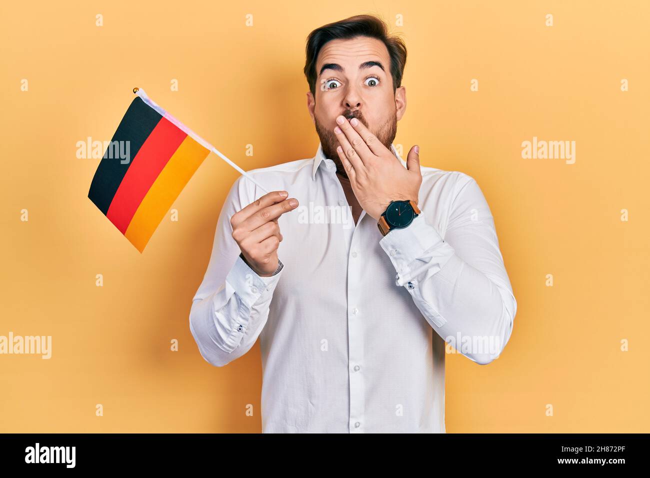 Handsome caucasian man with beard holding germany flag covering mouth ...
