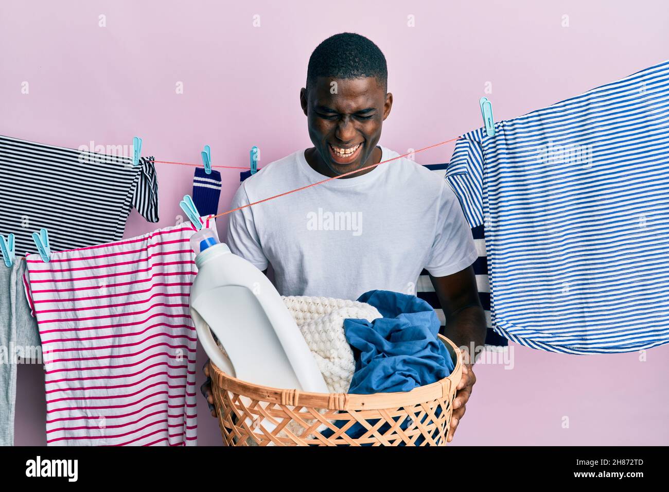 Young african american man holding laundry basket smiling and laughing ...