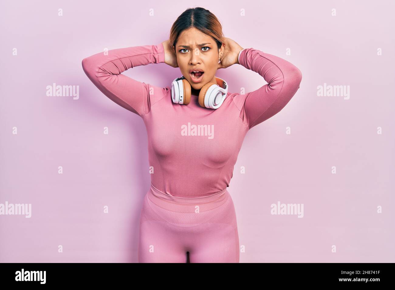 Beautiful hispanic woman wearing gym clothes and using headphones crazy ...