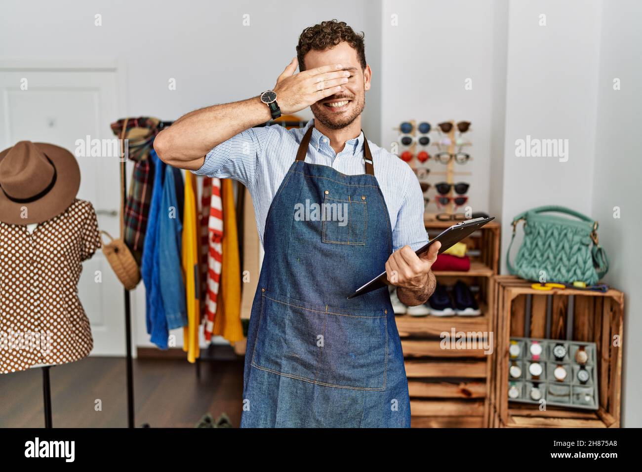 Handsome young man working as manager at retail boutique smiling and ...
