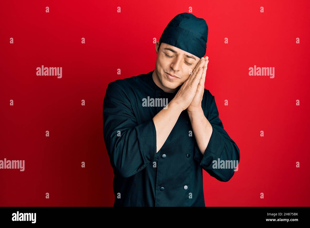 Handsome young man wearing professional cook uniform and hat sleeping ...