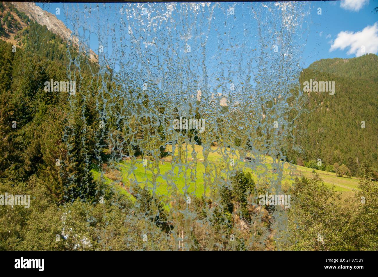 Tyrolean Alpine landscape as seen through a curtain of water from ...