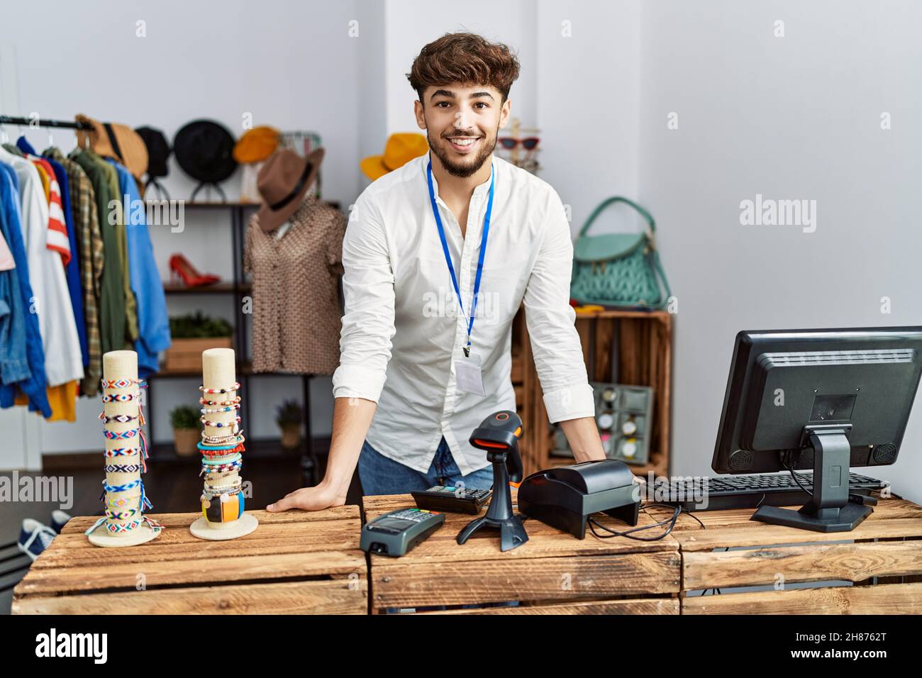 Young arab man shopkeeper smiling confident working at clothing store ...