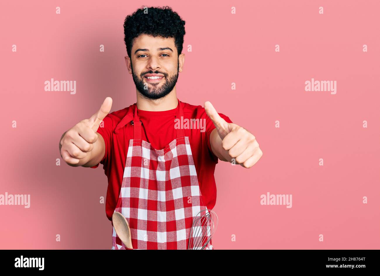 Young arab man with beard wearing cook apron approving doing positive ...