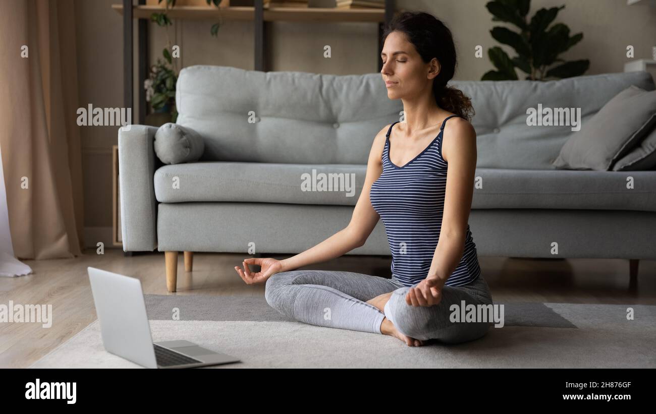 Young woman meditating by pc holding mudra feeling mental balance Stock ...