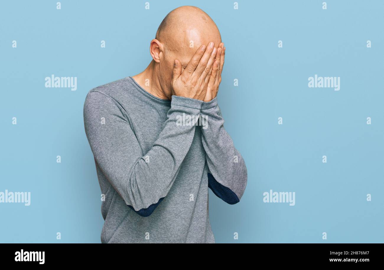 Bald man with beard wearing casual clothes with sad expression covering ...
