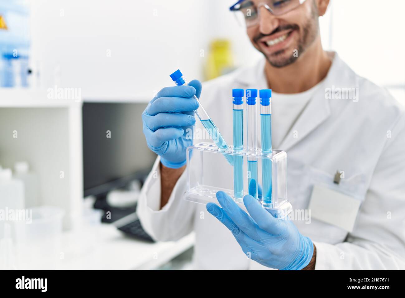 Handsome hispanic man working as scientific holding test tubes at ...