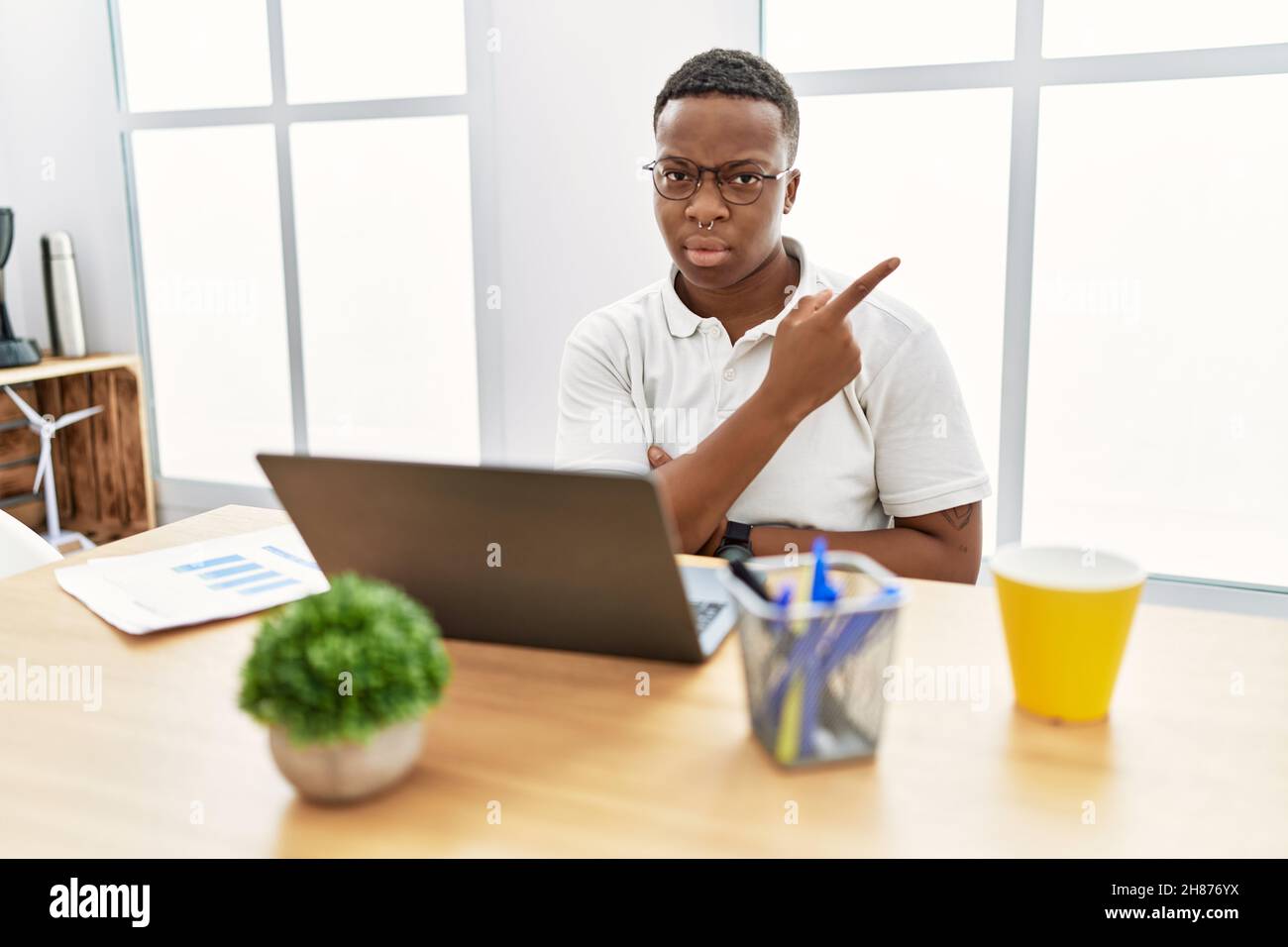 Young african man working at the office using computer laptop pointing ...