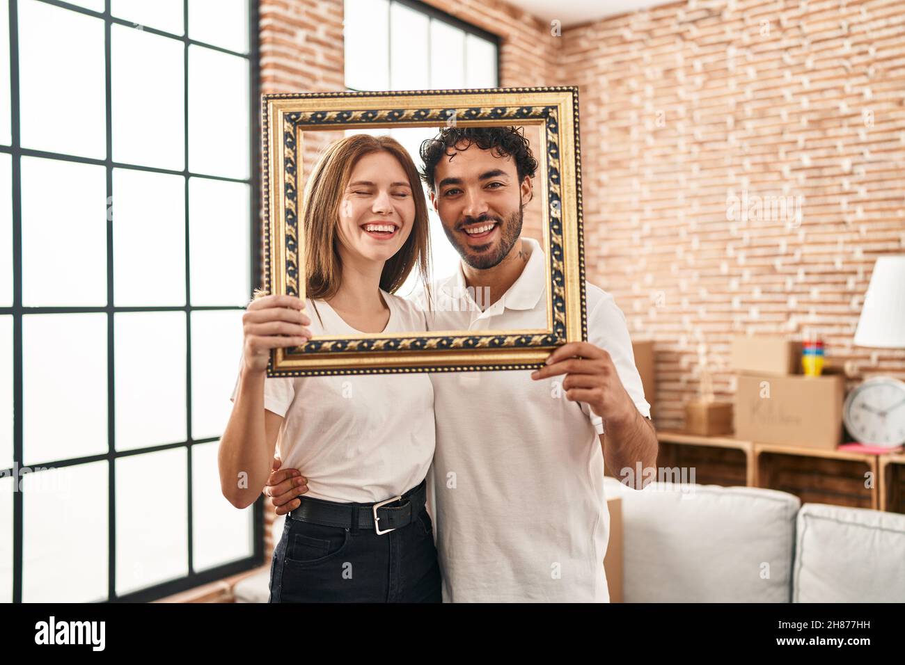 Young two people holding empty frame together smiling and laughing hard ...