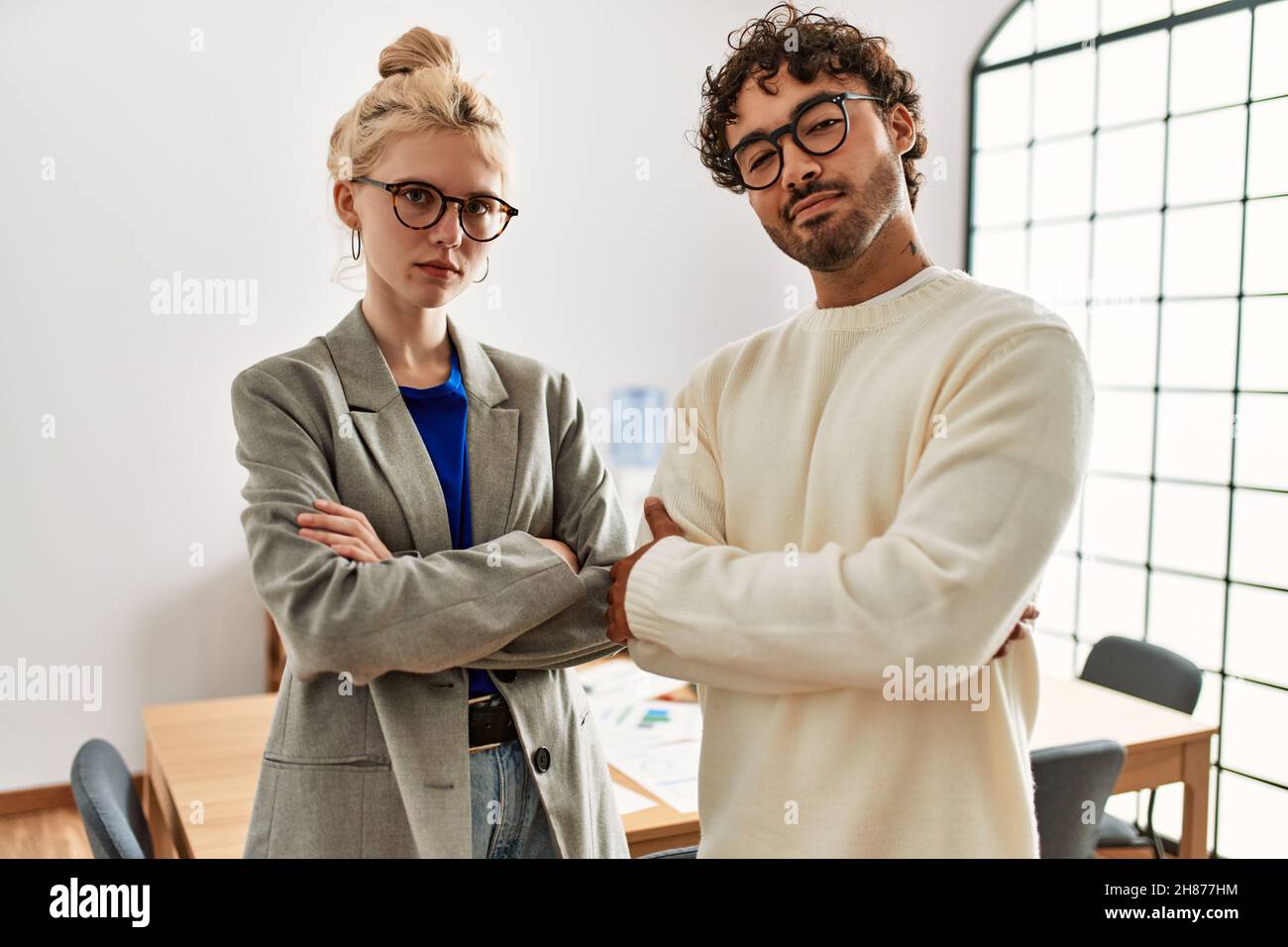 Two business workers standing with arms crossed gesture at the office ...