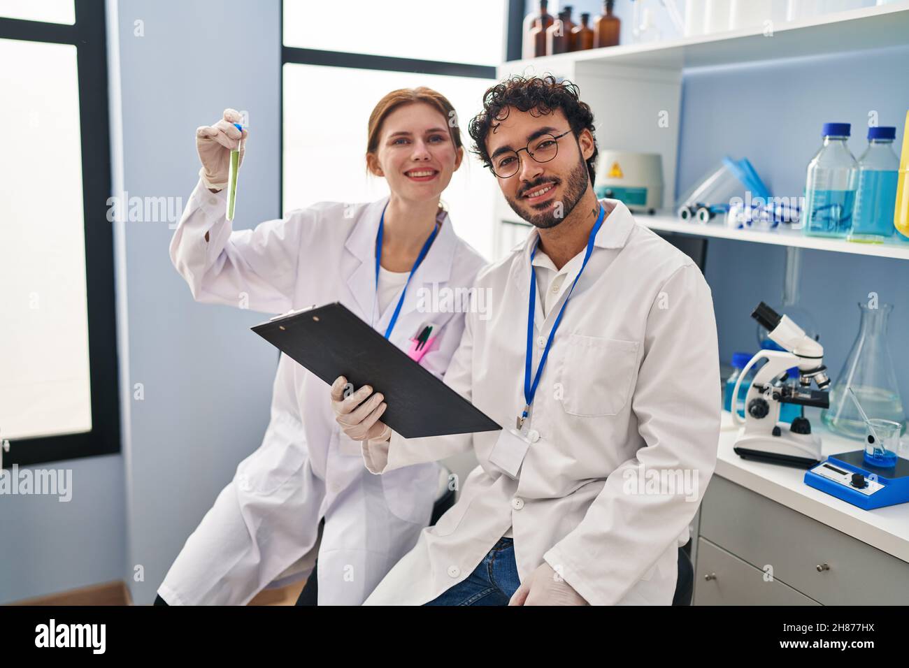Man and woman scientist partners holding test tube reading clipboard at ...