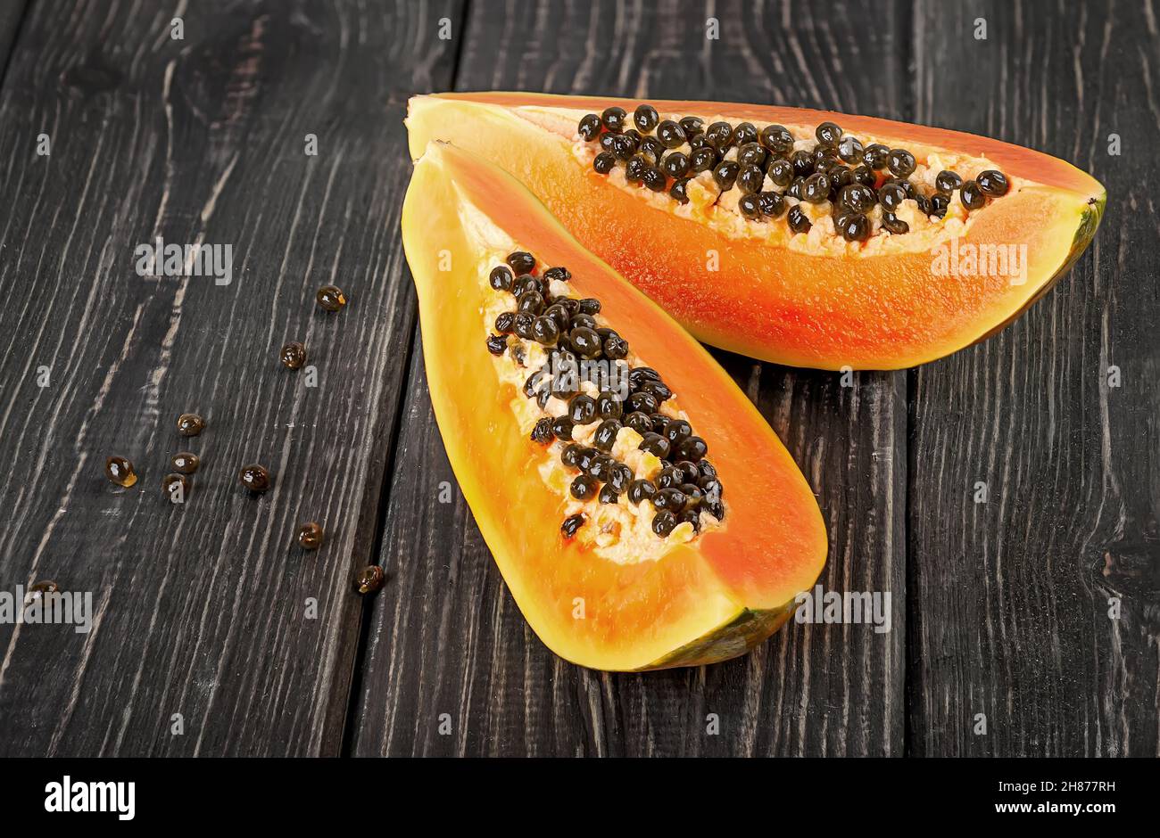 Two pieces of ripe papaya on a wooden table. Quarters of papaya on a ...