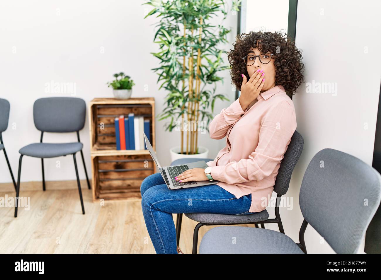 Young middle eastern woman sitting at waiting room working with laptop ...