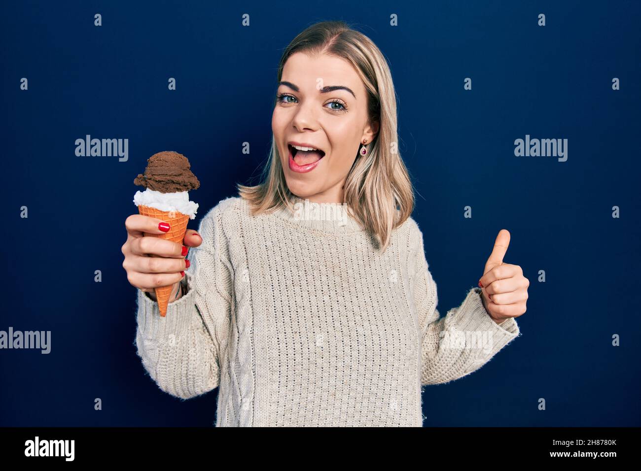 Beautiful caucasian woman eating ice cream pointing thumb up to the ...