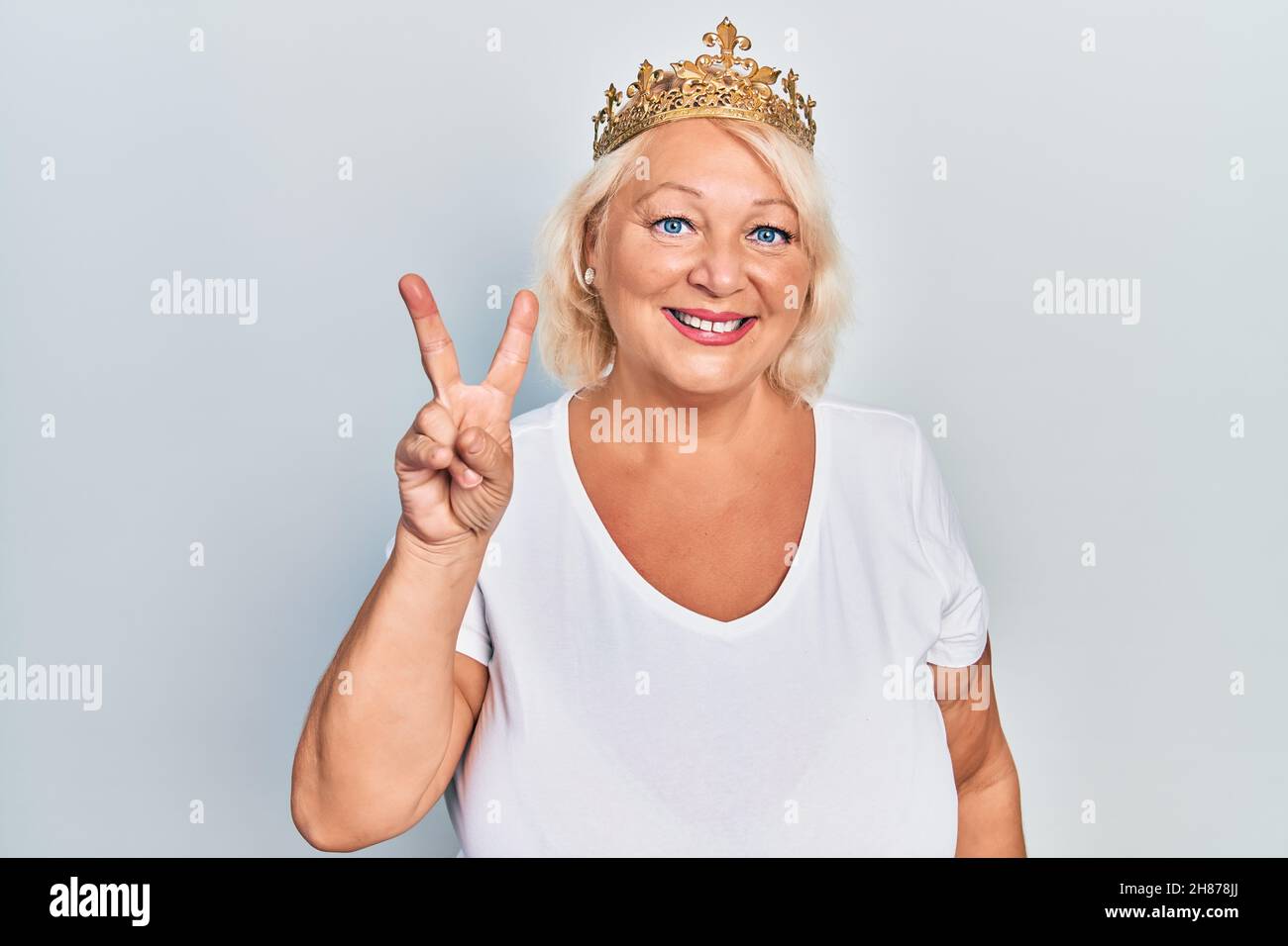 Middle age blonde woman wearing queen crown smiling with happy face ...