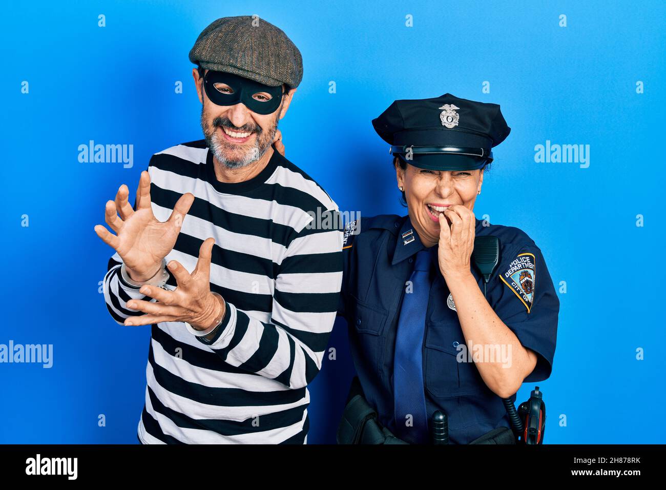 Middle age couple of hispanic woman and man wearing thief and police ...