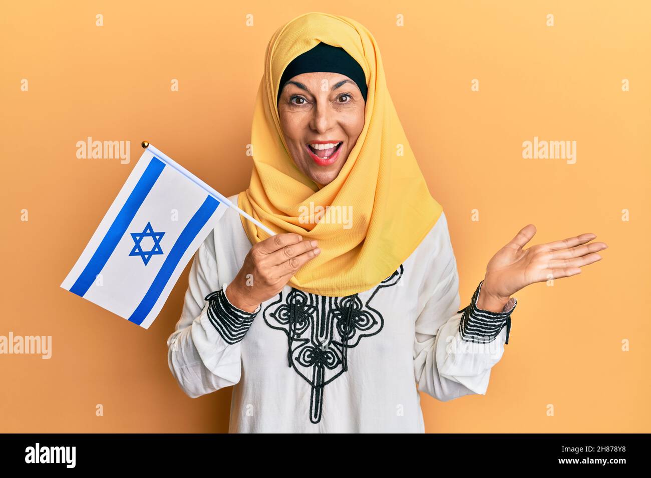 Middle age hispanic woman wearing hijab holding israel flag celebrating ...