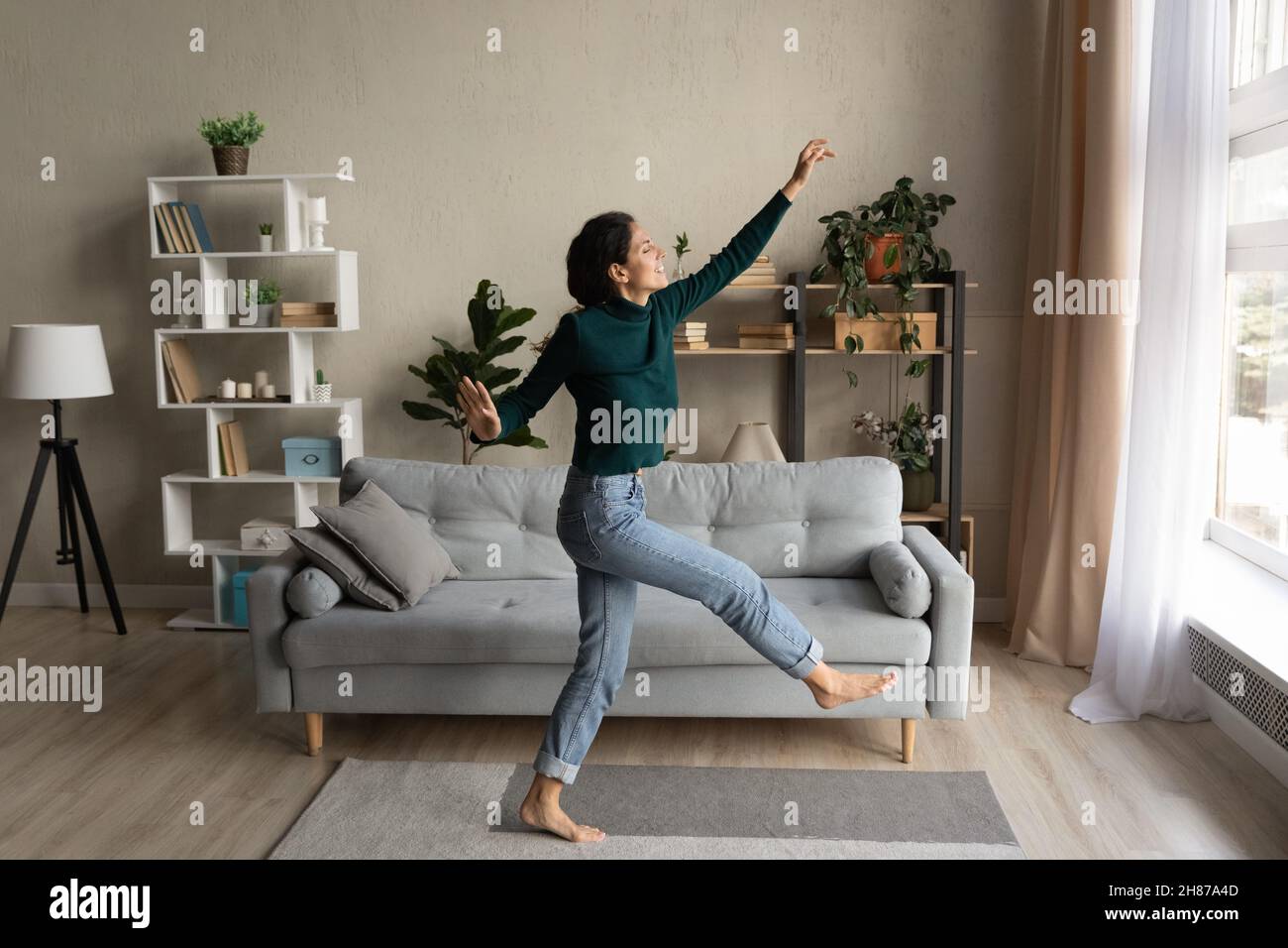 Overjoyed happy millennial hispanic woman dance at modern living room ...