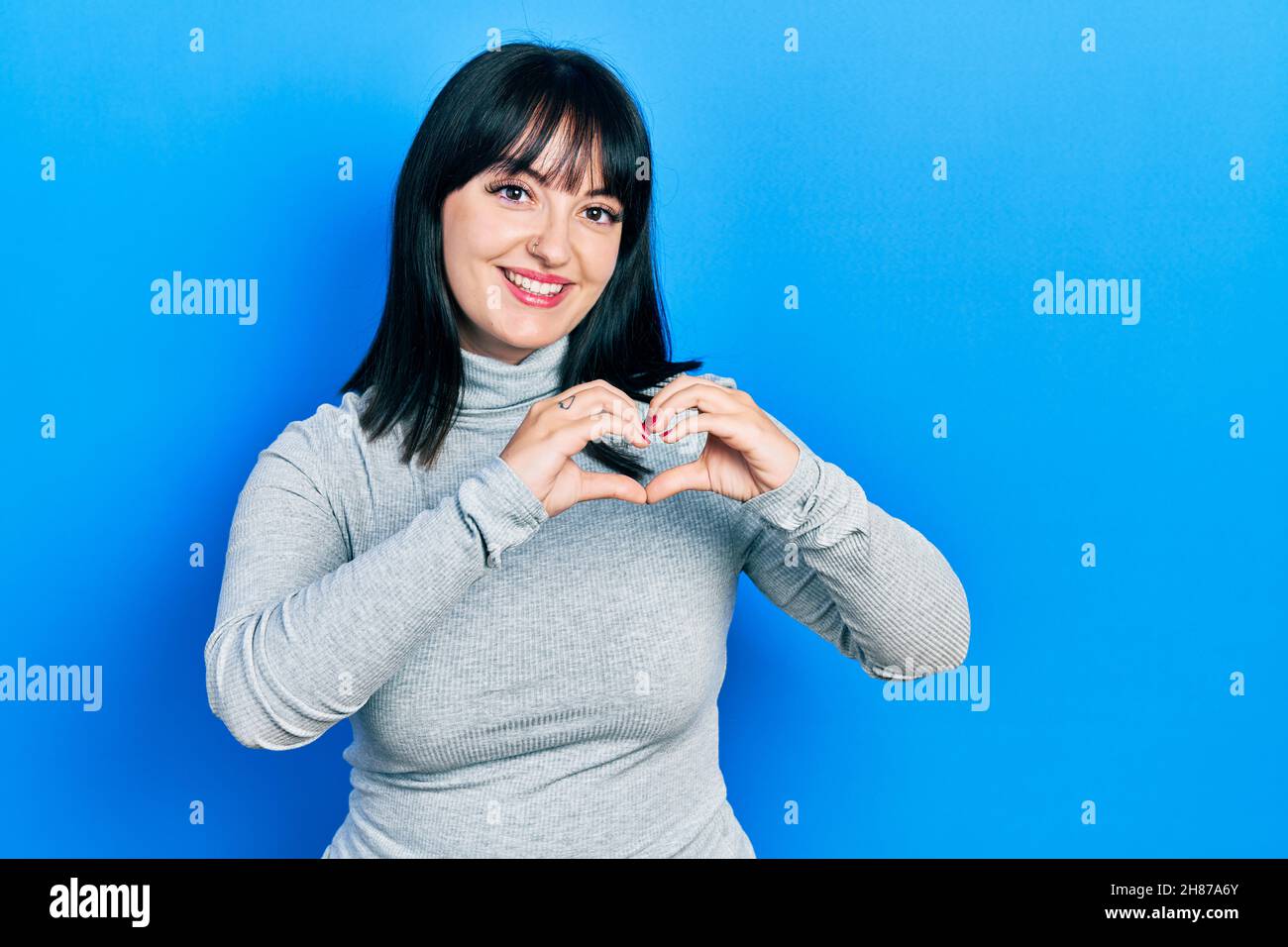 Young hispanic woman wearing casual clothes smiling in love doing heart ...