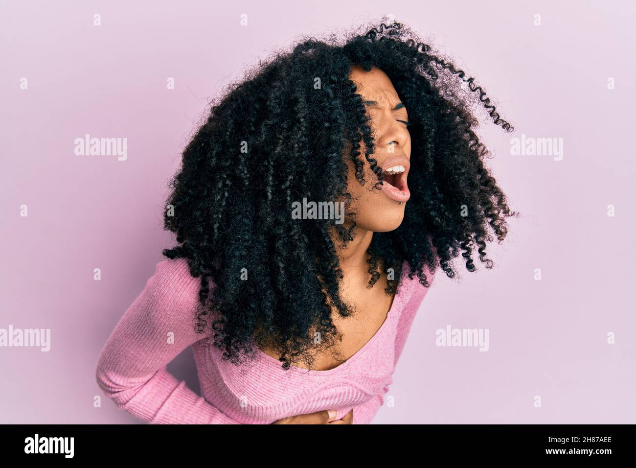 African american woman with afro hair wearing casual pink shirt with ...