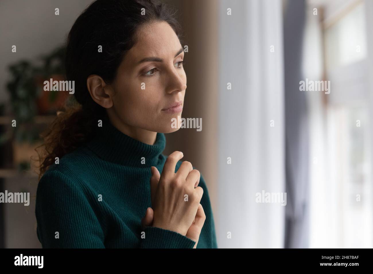 Worried young latin woman look at window feel lonely sad Stock Photo ...