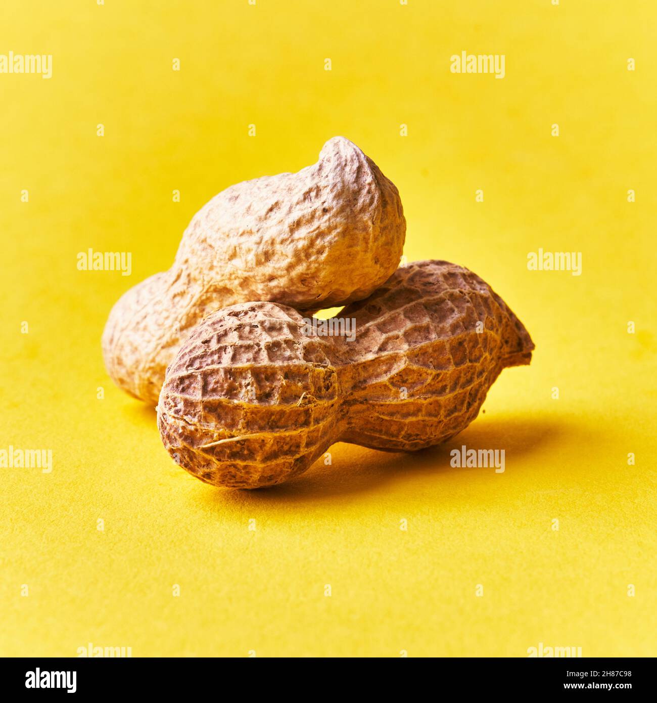 Two peanuts with shell on a yellow background Stock Photo - Alamy