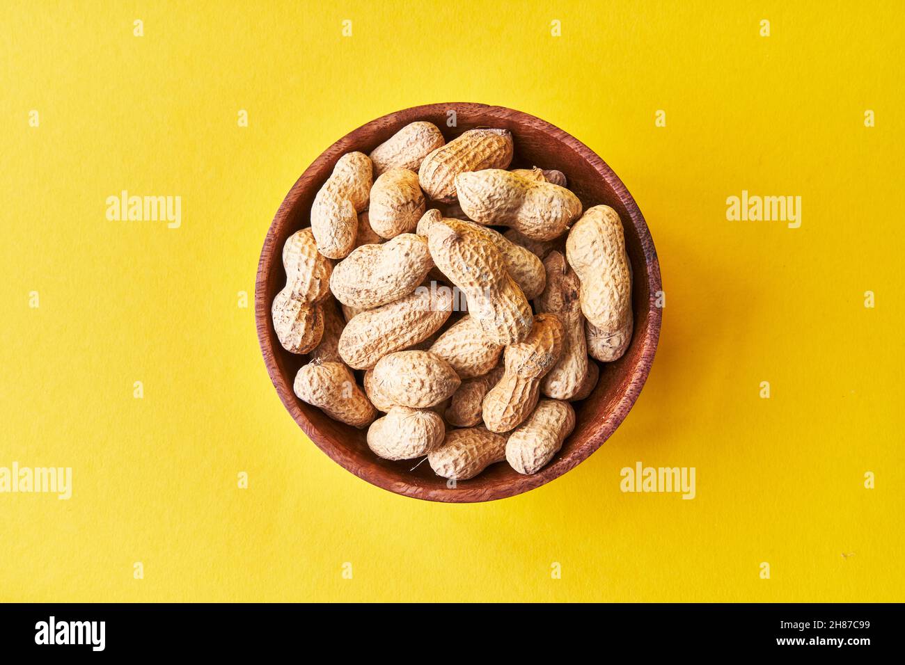 Bowl of peanuts with shell on a yellow background Stock Photo - Alamy