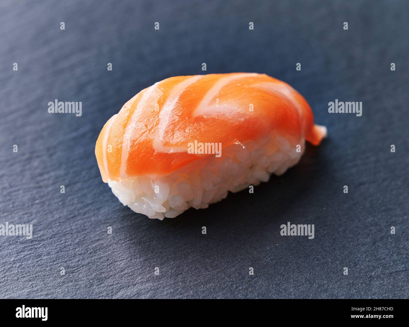 Single salmon nigiri sushi on a blackboard surface Stock Photo - Alamy