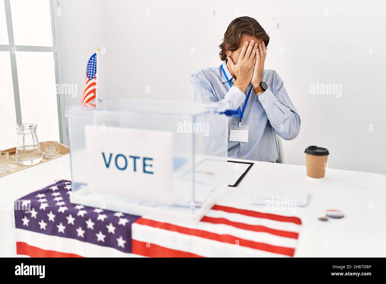 Handsome middle age man sitting at voting stand with sad expression ...