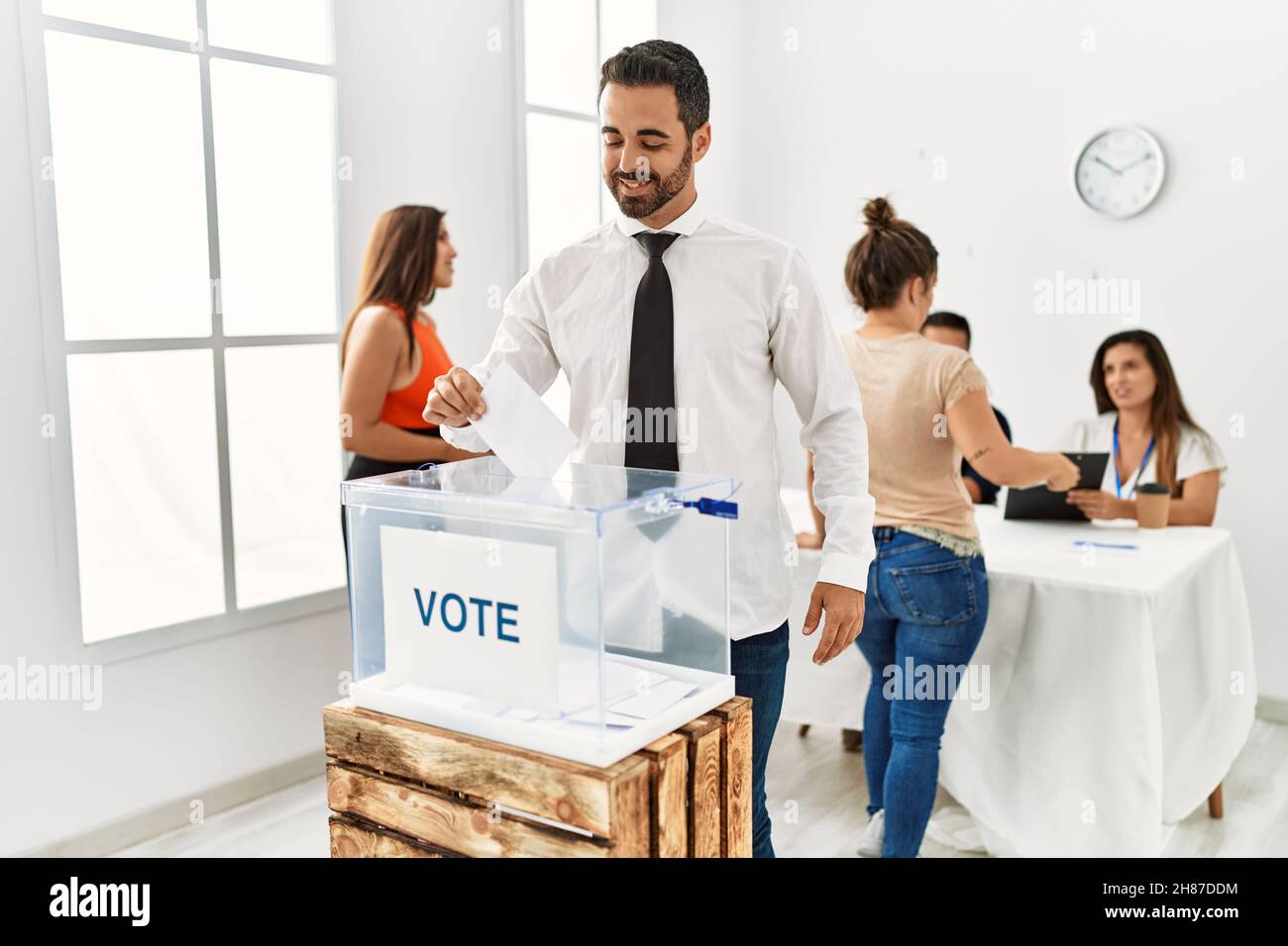 Young voter man smiling happy putting vote in voting box standing by ...