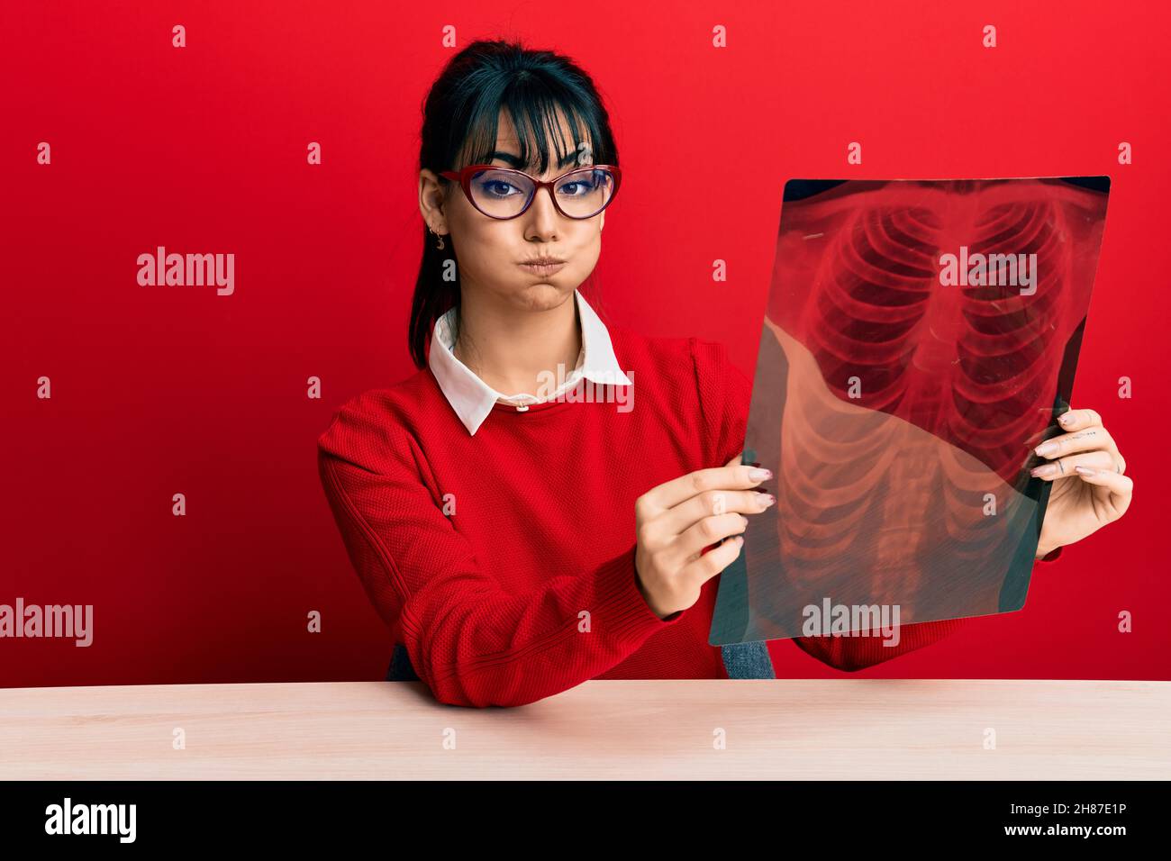 Young brunette woman with bangs holding chest radiography puffing ...