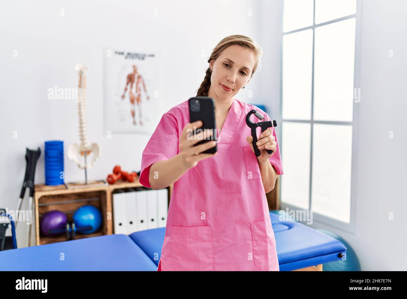 Young caucasian woman wearing physiotherapist uniform having video call ...