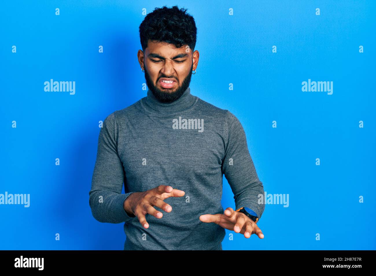 Arab man with beard wearing turtleneck sweater disgusted expression ...