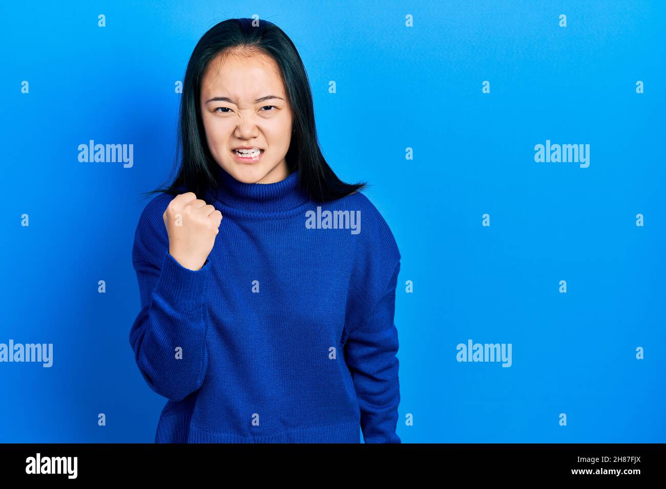 Young chinese girl wearing casual clothes angry and mad raising fist ...