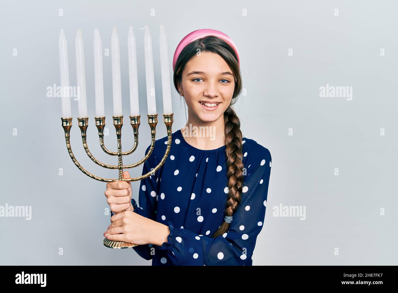 Young brunette girl holding menorah hanukkah jewish candle smiling and ...