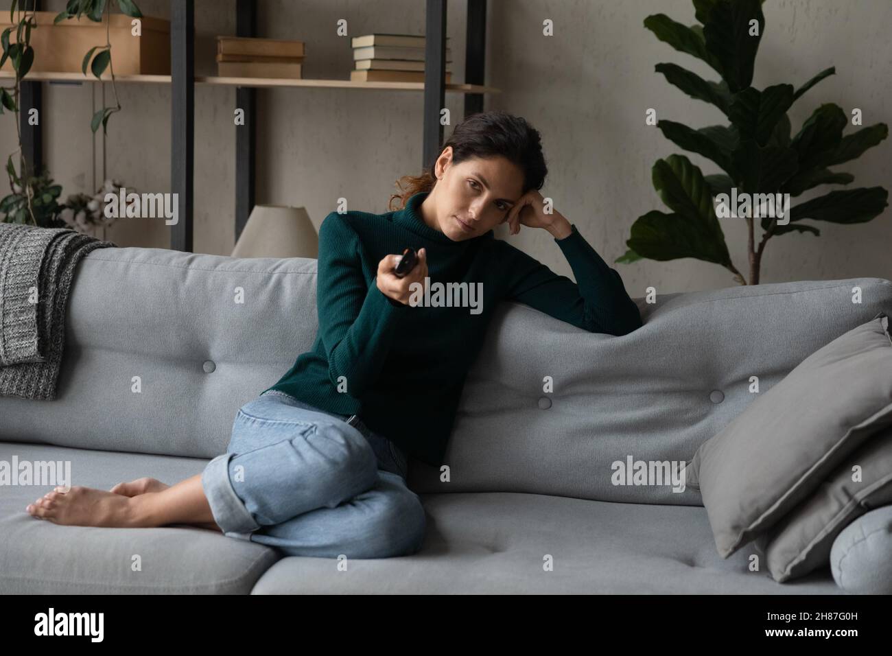 Unhappy millennial hispanic woman spend time alone before tv set Stock ...