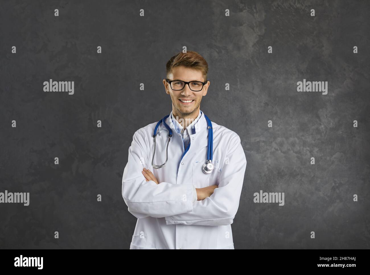Studio portrait of happy male doctor standing with arms folded and ...