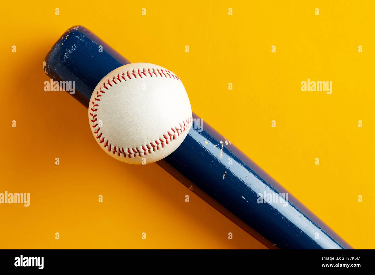 Baseball ball on a wooden baseball bat on yellow background with copy ...