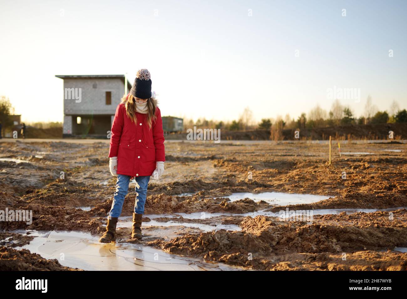 Happy young girl playing with thin ice puddles formed on the frozen ...