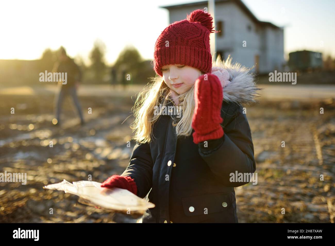Happy young girl playing with thin ice puddles formed on the frozen ...