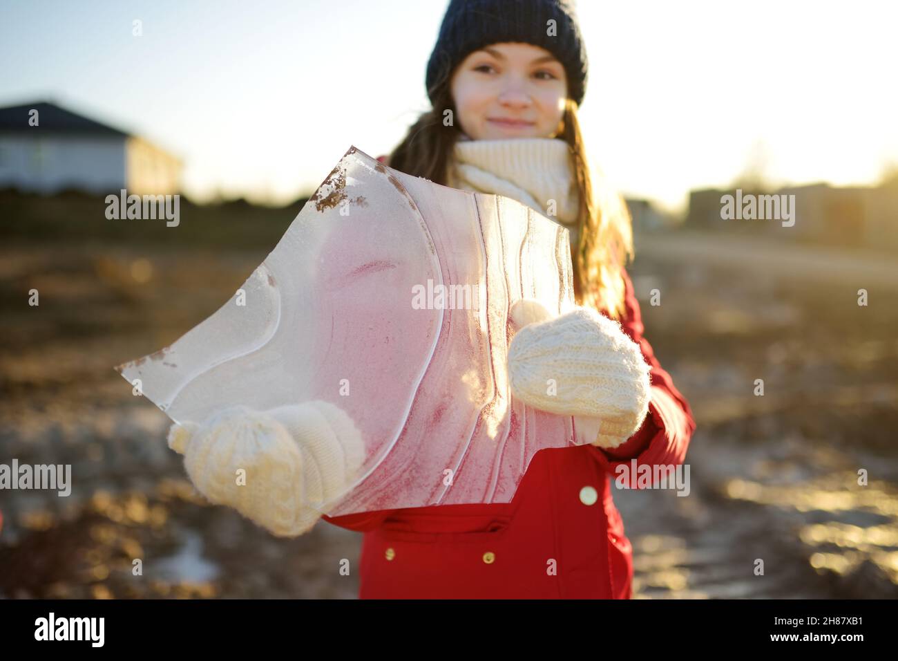 Happy young girl playing with thin ice puddles formed on the frozen ...