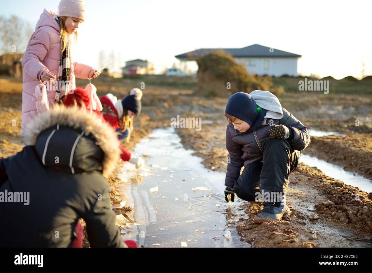 Group of children playing with thin ice puddles formed on the frozen ...