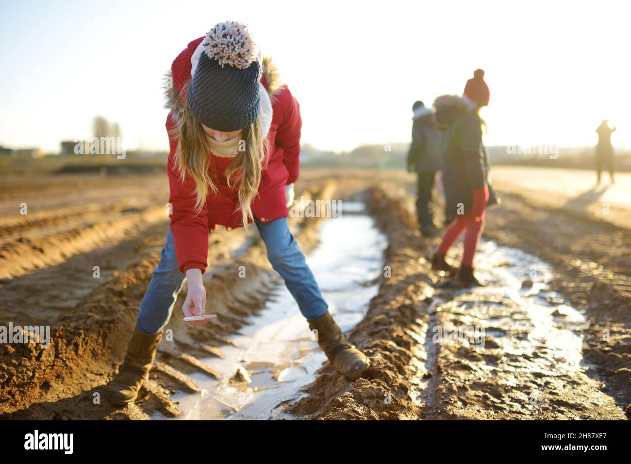 Group of children playing with thin ice puddles formed on the frozen ...