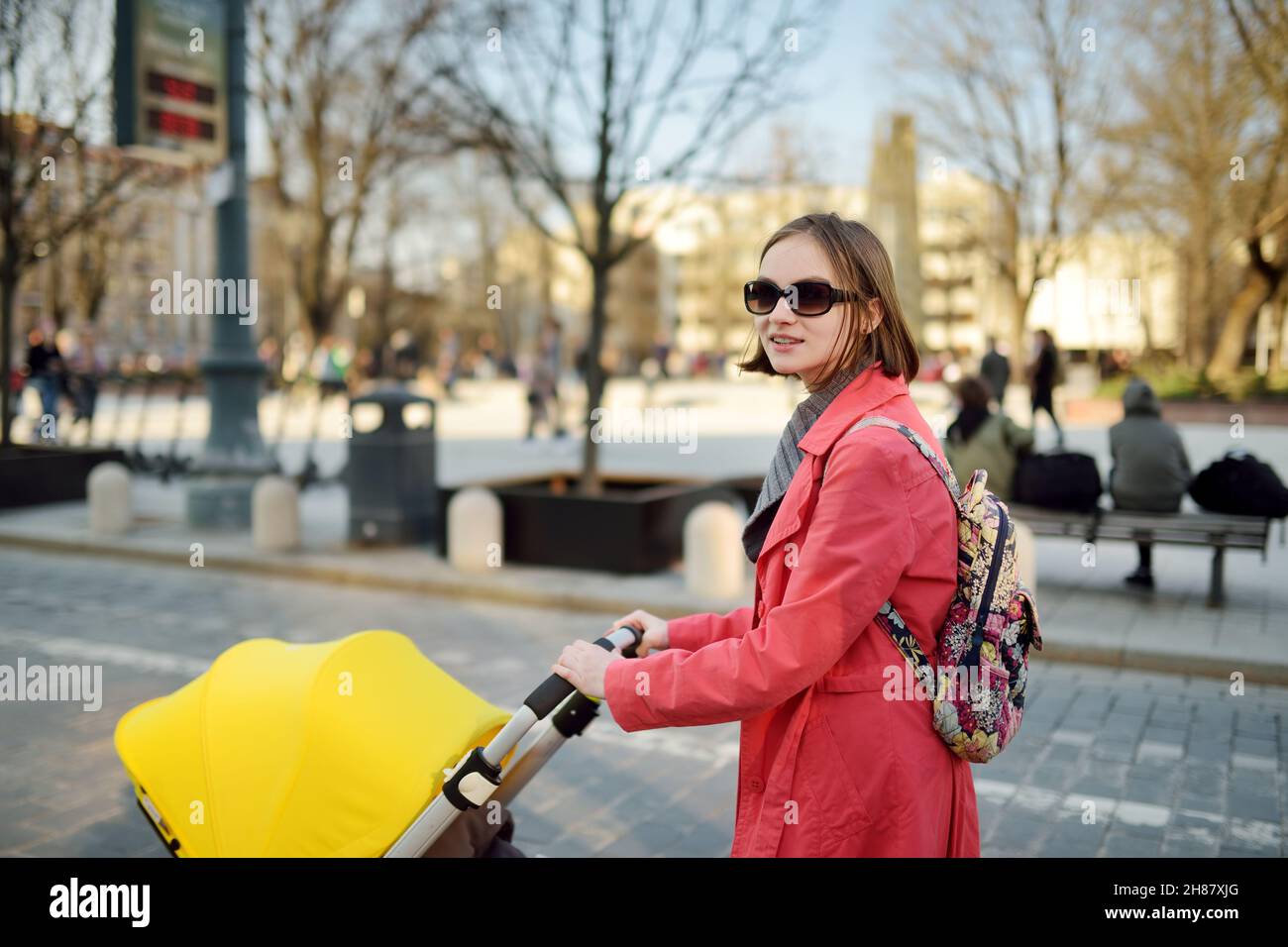 Cute big sister walking in a city with baby brother in pushchair ...