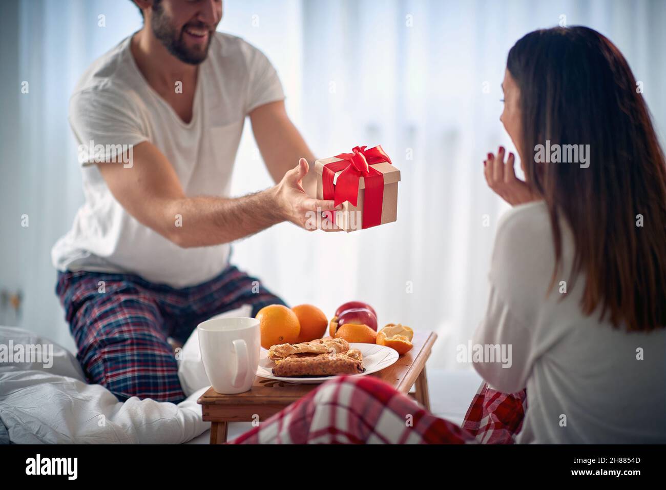 Christmas gift with red ribbon.Man surprise his happy girlfriend Stock ...